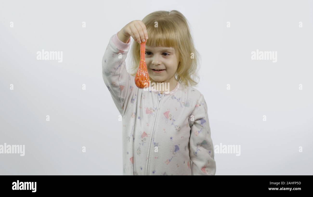 Child having fun making orange slime. Kid playing with hand made toy ...