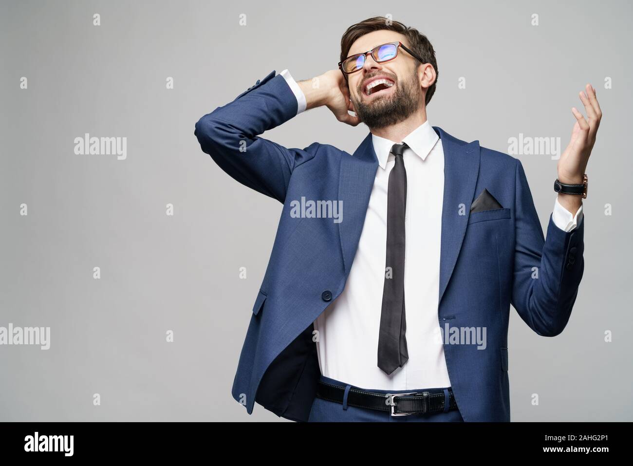 Very happy successful winner gesturing businessman over grey background ...