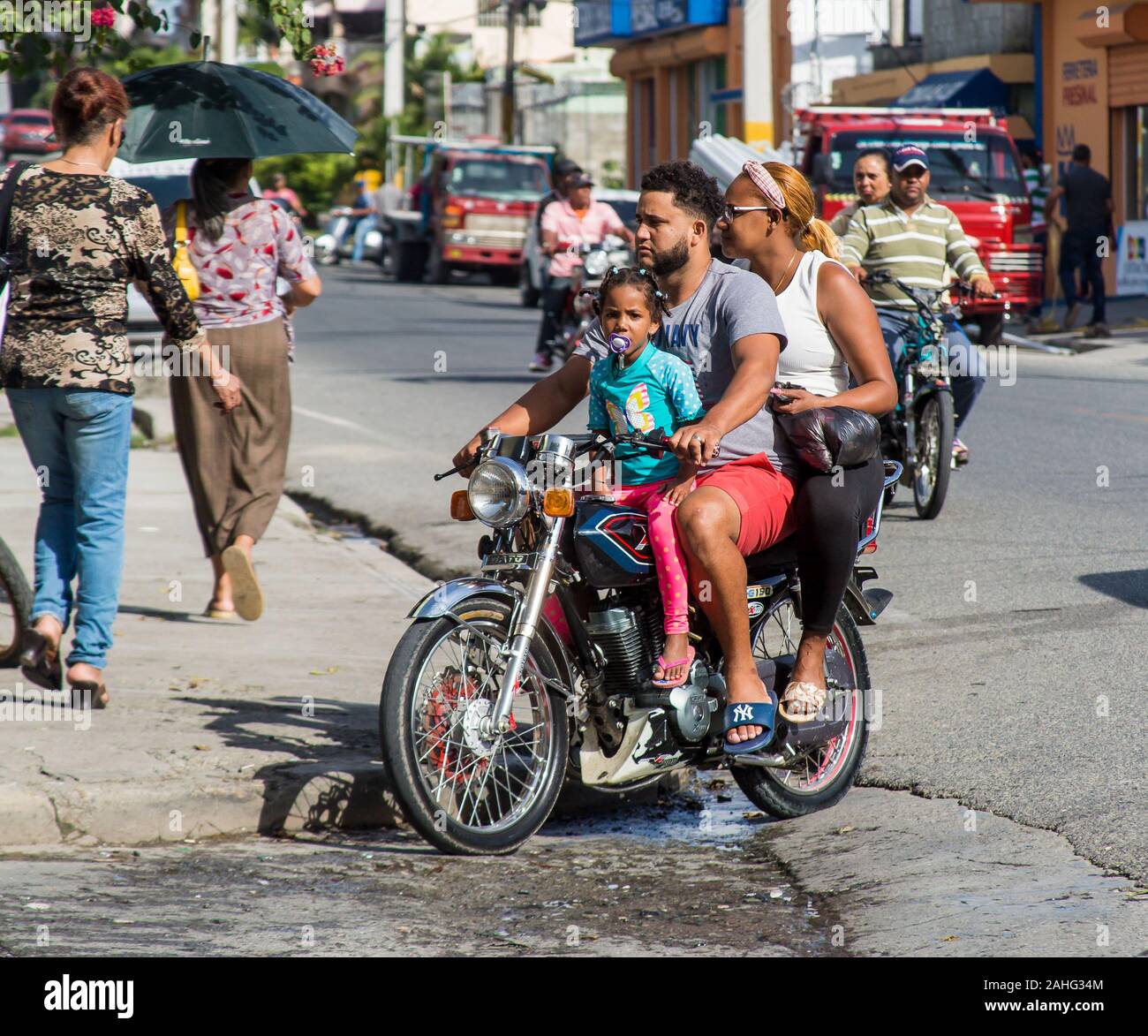 dramatic image of two adults and one child riding on one motorbike in a ...