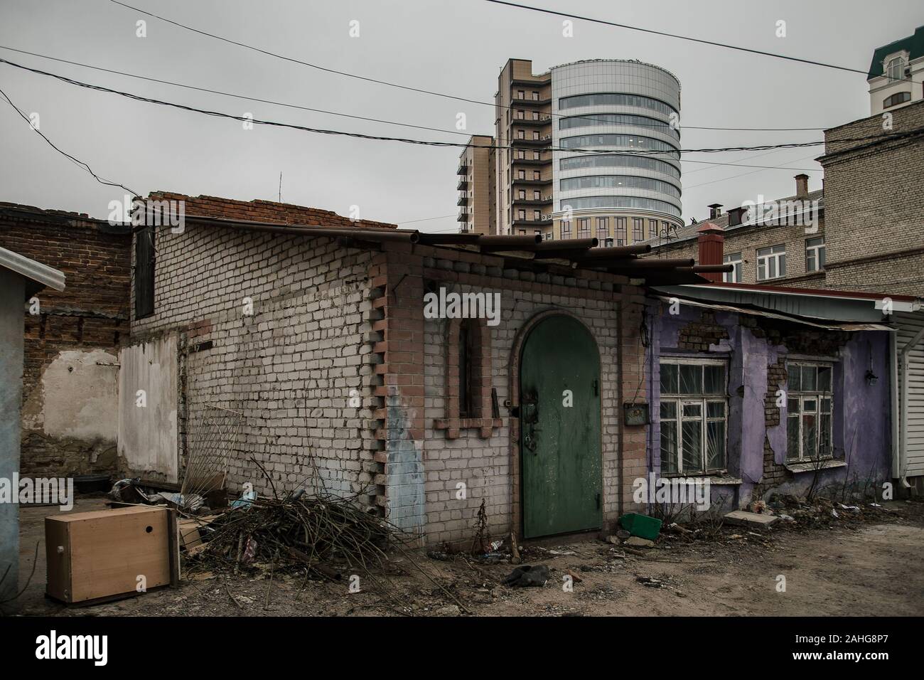 Old shabby house on background of new modern business center. Contrast ...