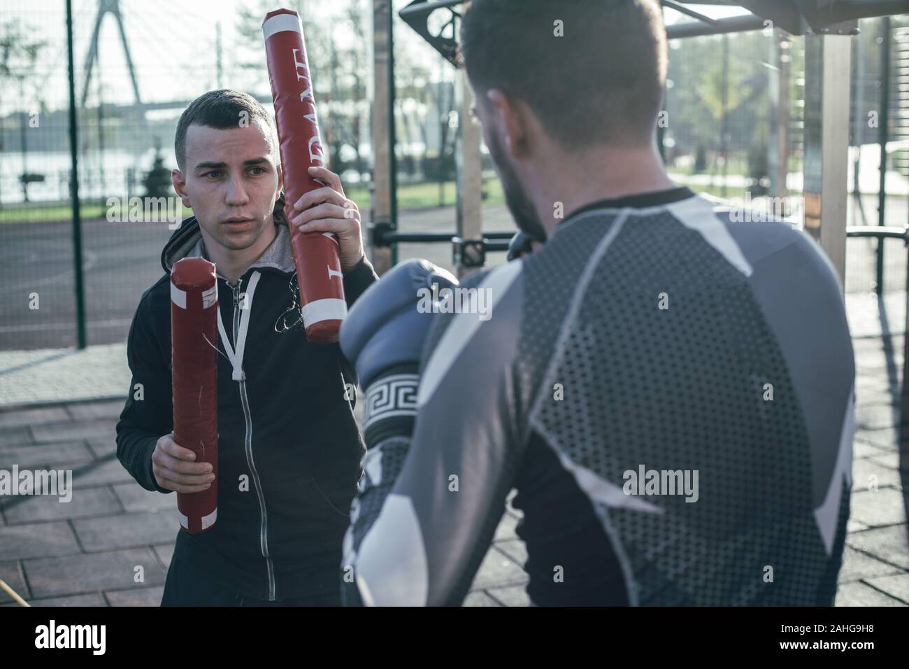 Confident trainer putting boxing stick up and waiting for the punch ...