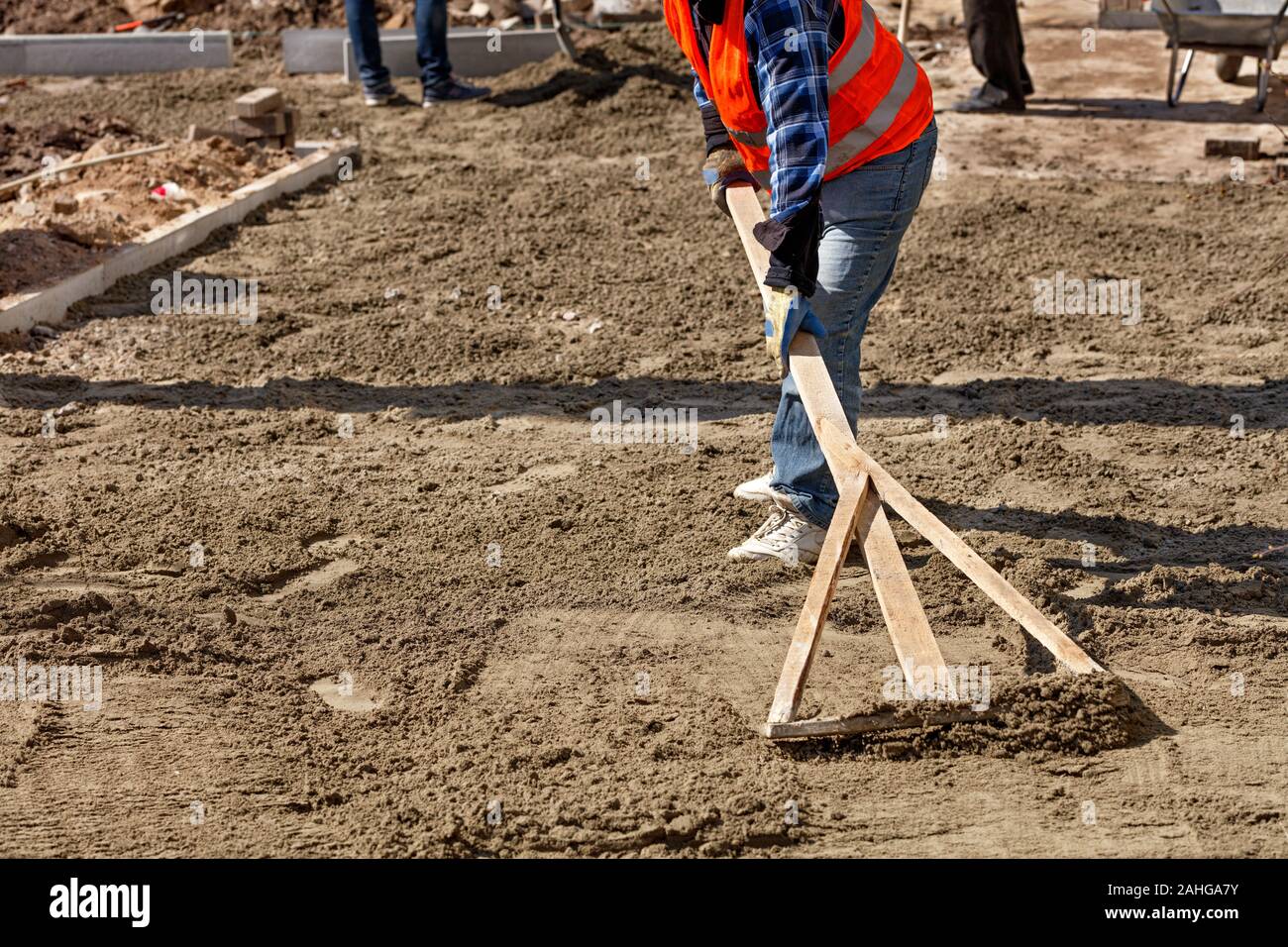 A worker levels the sand base with a wooden level to begin laying ...