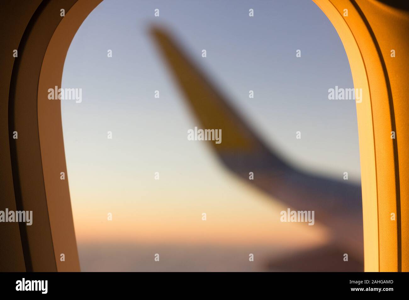 Sunlight on plane window with wing blurred on background. Air ...