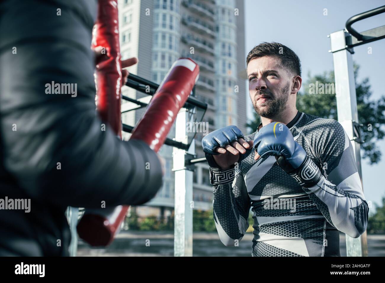 Confident boxer frowning while having training at the sports ground ...