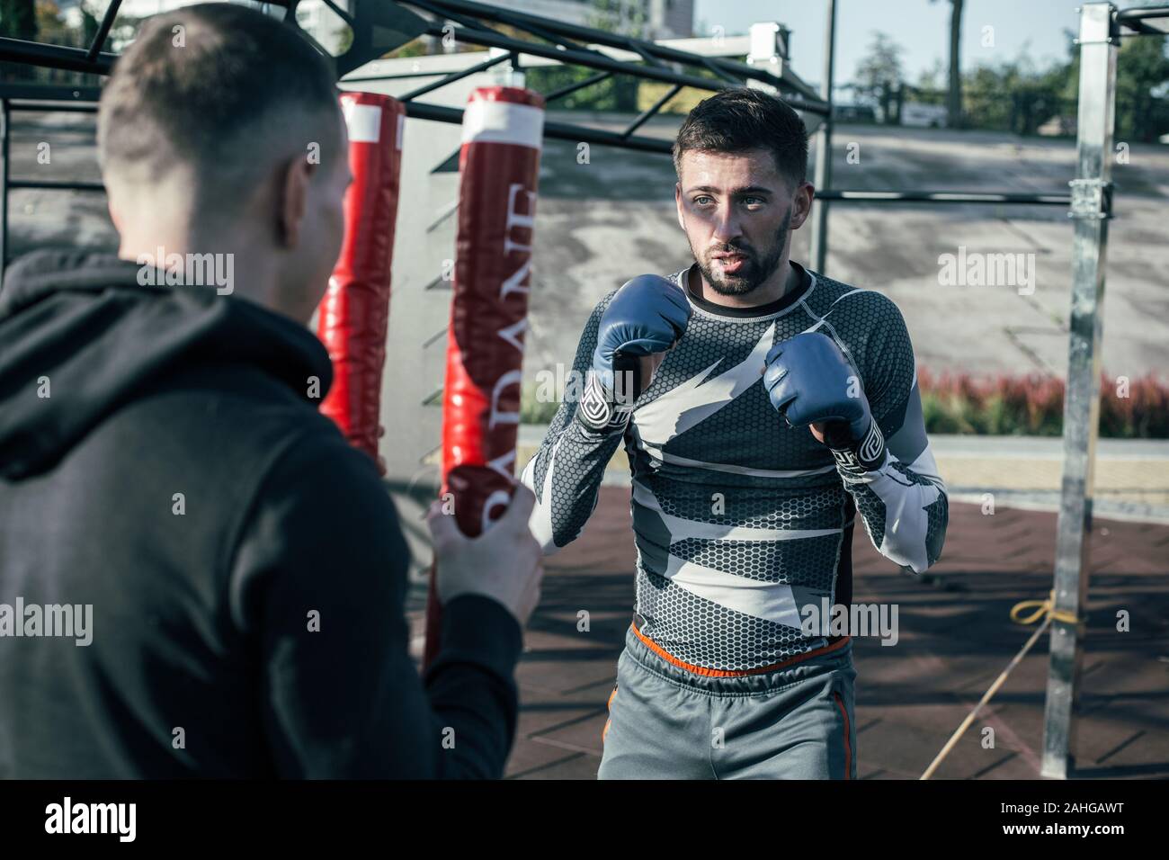 Serious boxer looking at the trainer while mastering his punches Stock ...
