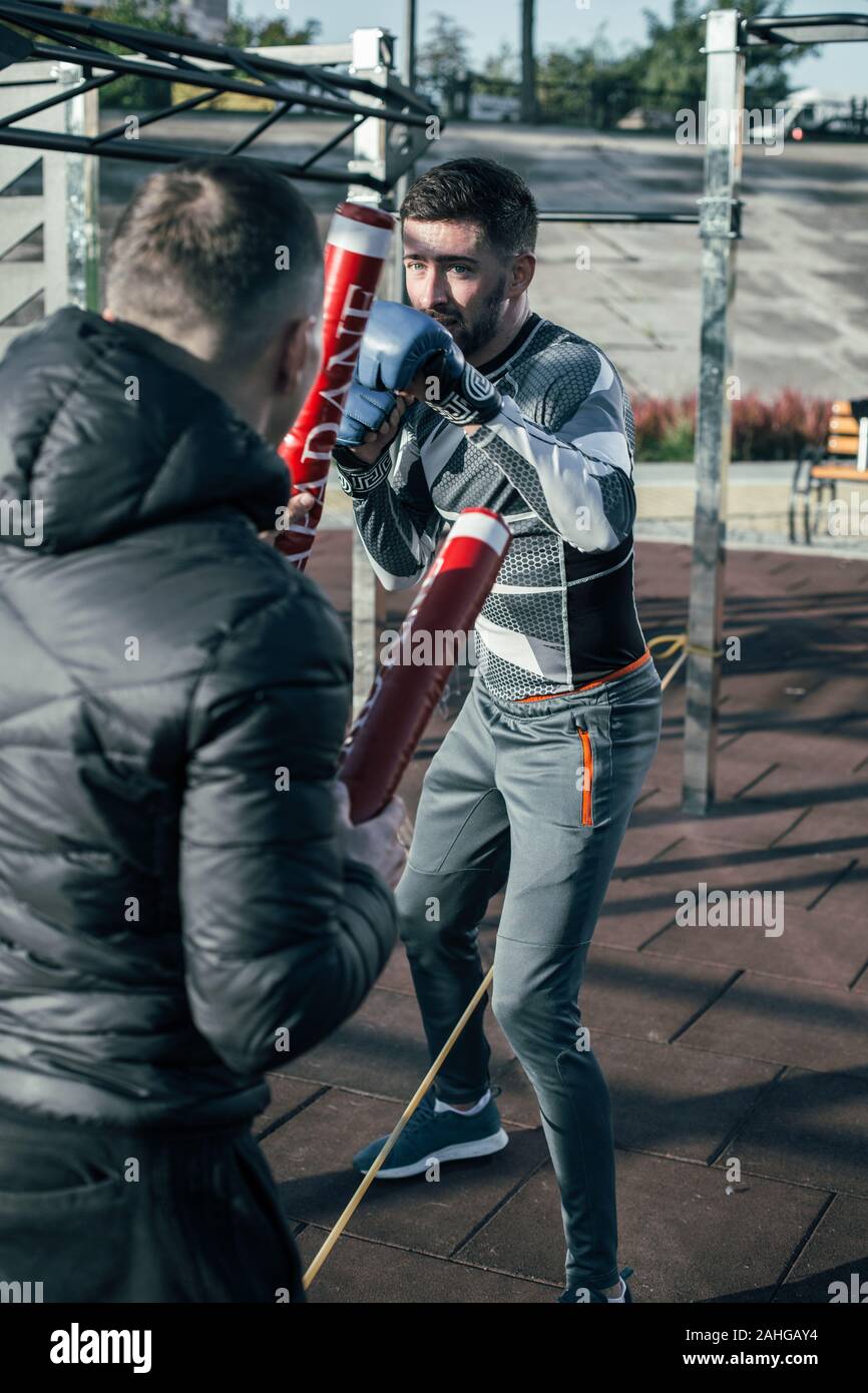 Full length of the active sportsman training with red boxing sticks ...