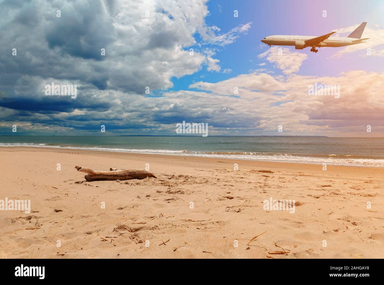Passenger airplane flying over above island clouds over waves touching ...