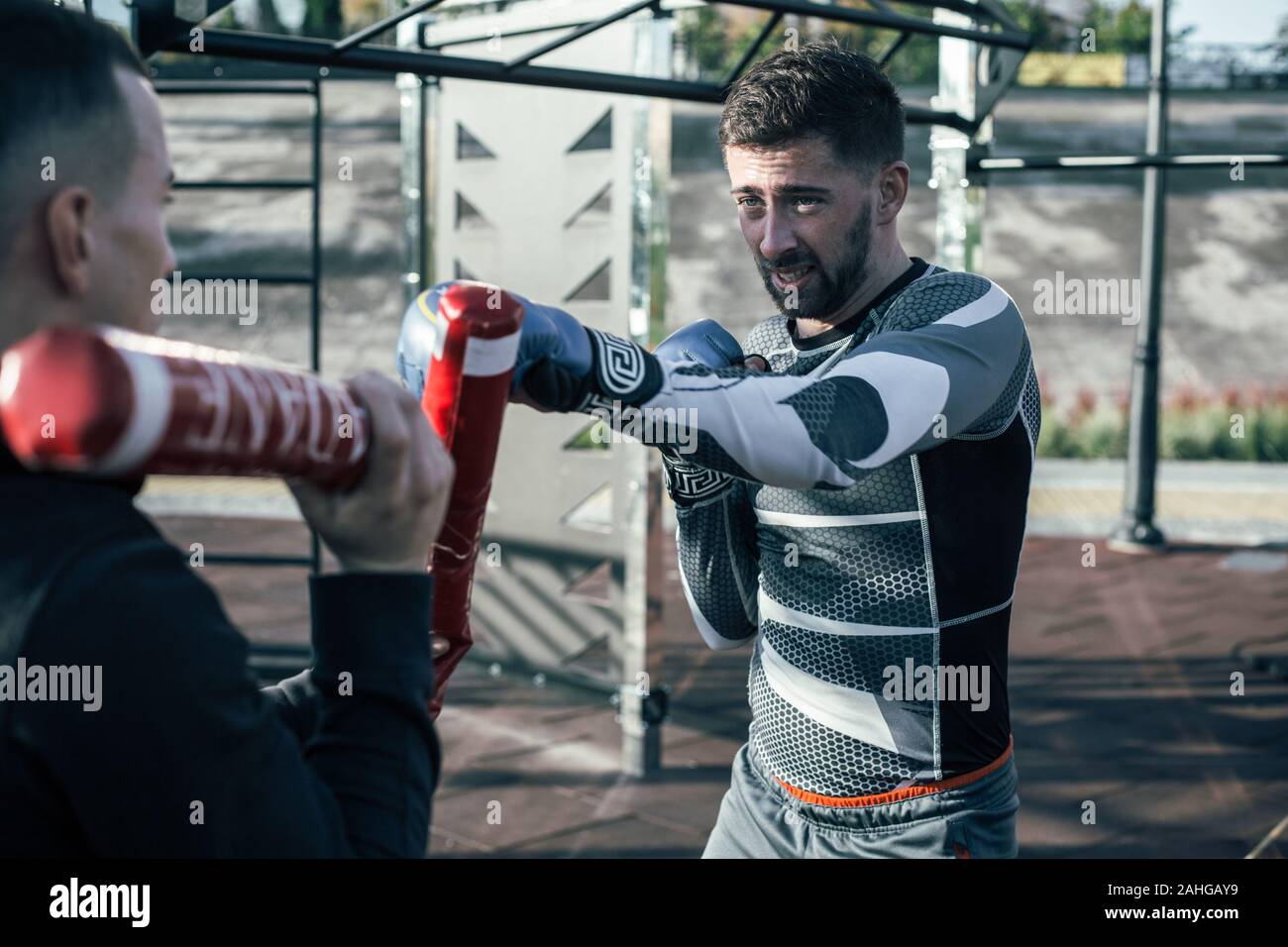 Serious boxer mastering his punch and looking at the trainer Stock ...