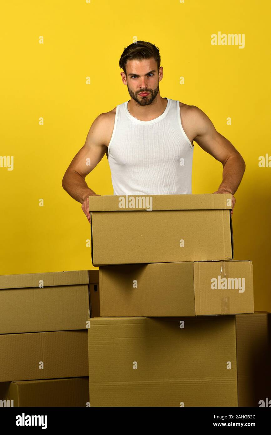 Delivery and moving in concept. Guy with cartons on yellow background ...