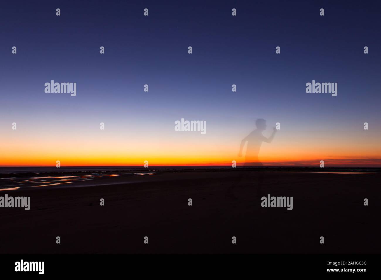 Long exposure of ghost silhouette of man running on sand beach at ...