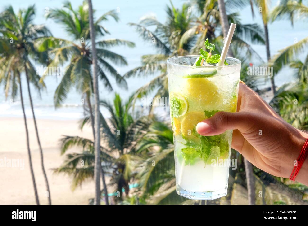 A young Asian man’s hand holding a virgin mojito cocktail brightly ...