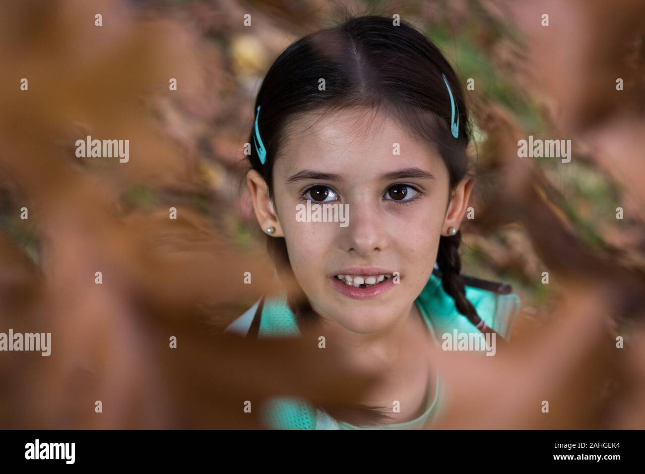 Adorable little girl closeup framed by brown leaves. Portrait of cute ...