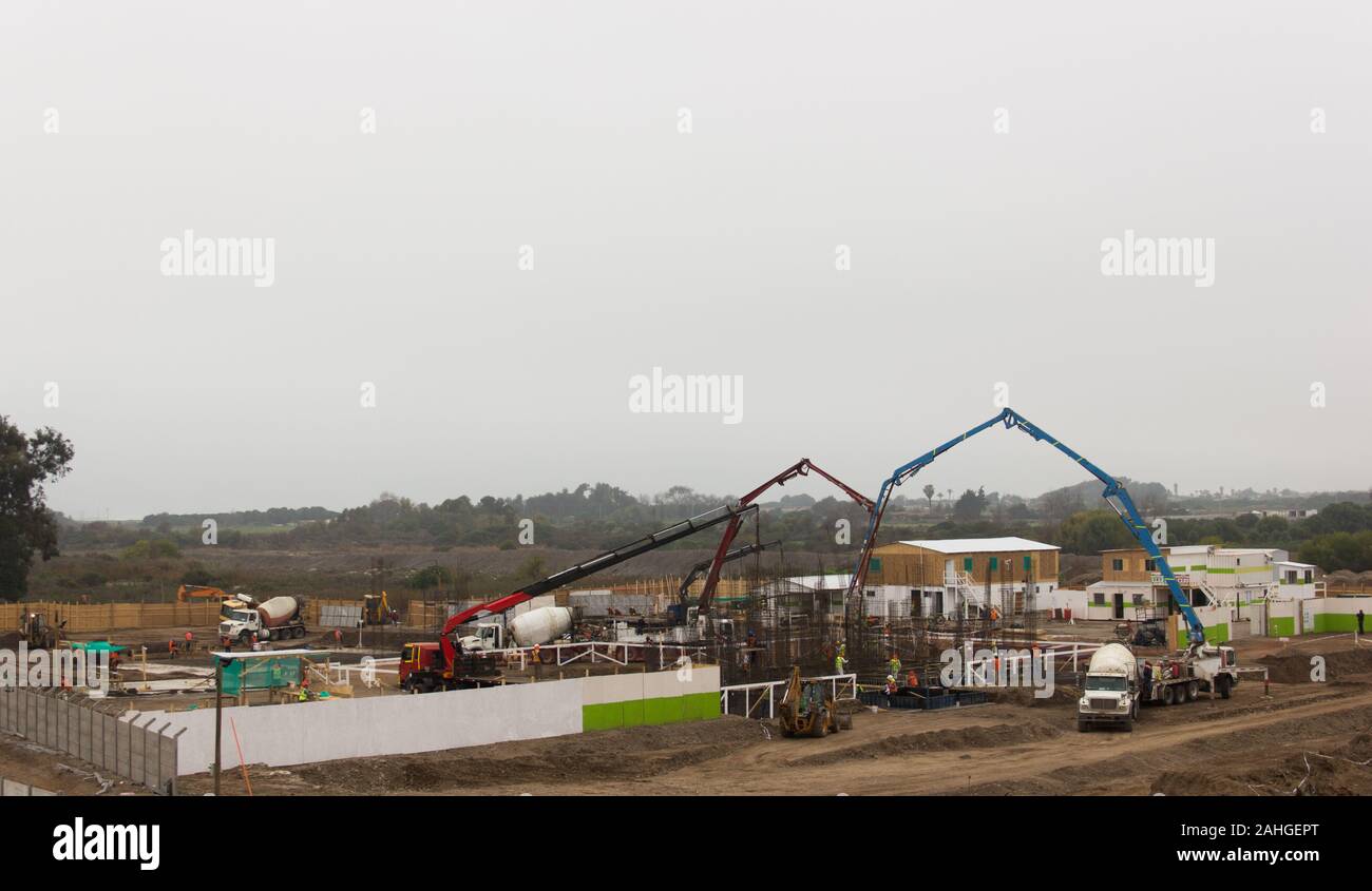 Apartment building construction site with trucks, workers and cranes on ...