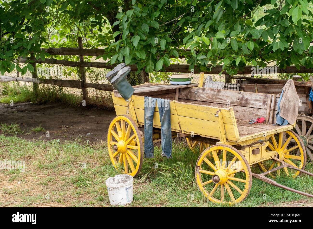 Old wooden rural cart in country village farm yard with boots and ...