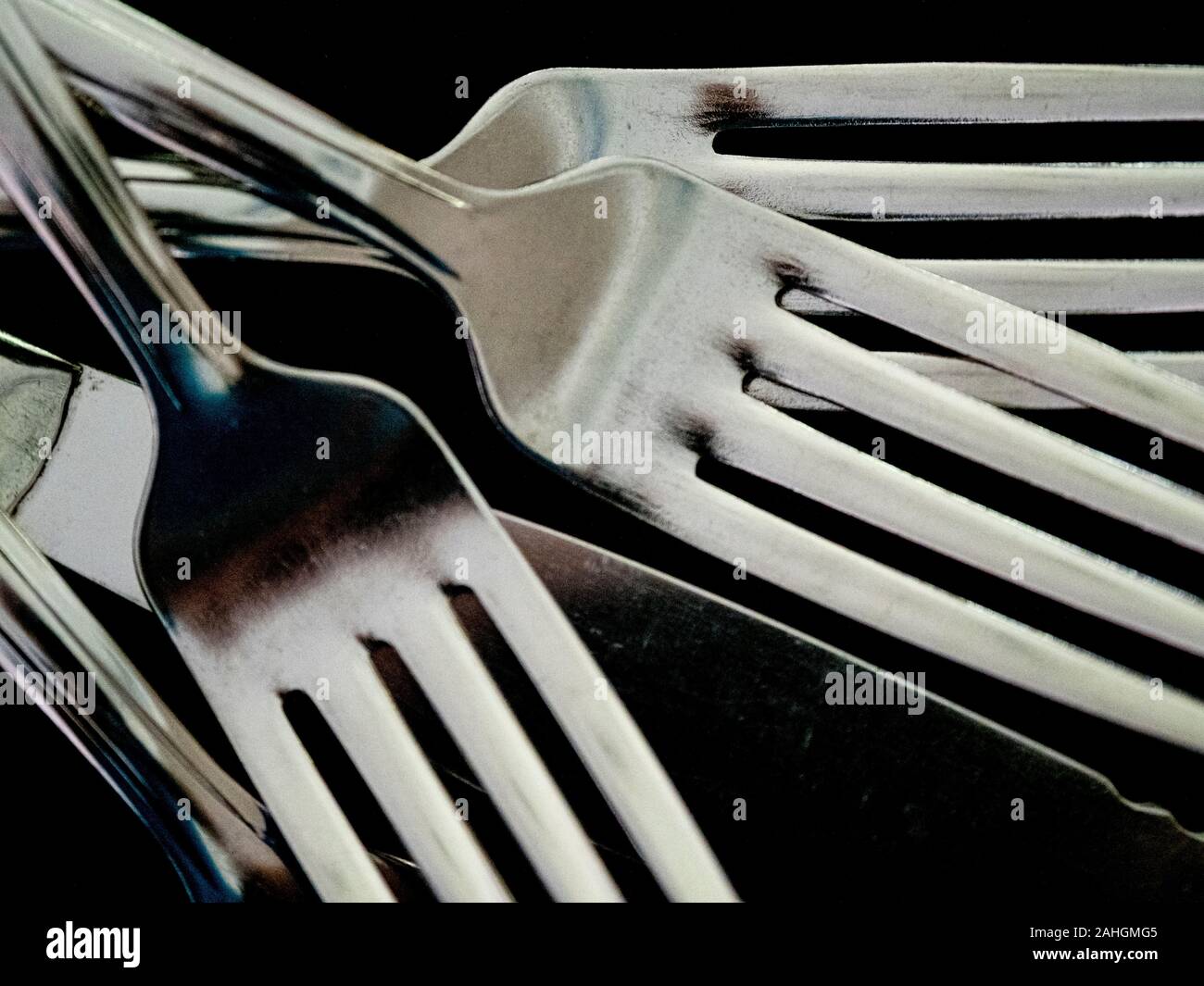 Closeup of a group of silverware forks against a black background Stock ...
