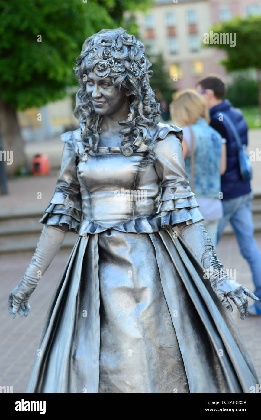 Living sculptures. Painted in silver color on the street posing a man ...