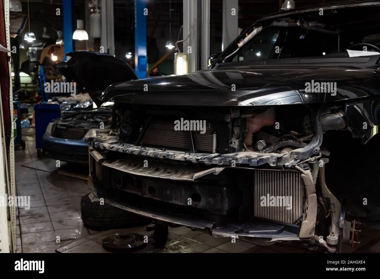 Used black car disassembled without bumper and wheels on a four-post ...