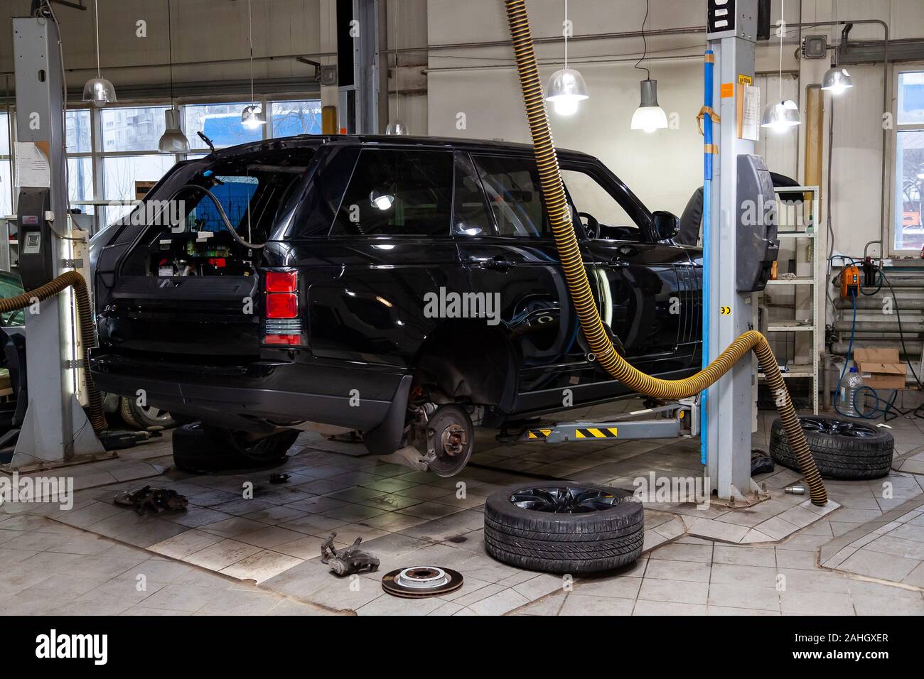 Used black car disassembled without bumper and wheels on a four-post ...