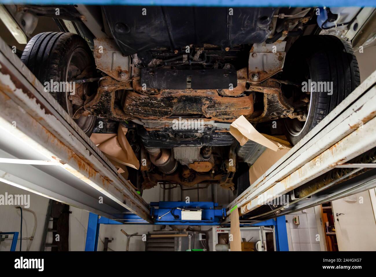 The bottom of the car lifted on a lift covered with brown and orange ...