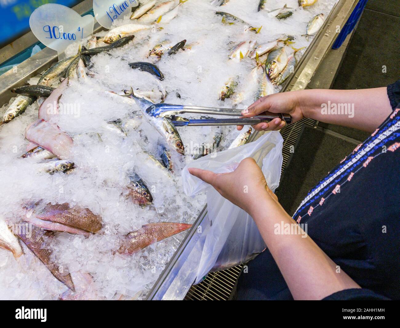Woman picking fish into bioplastic bag at seafood market Stock Photo ...