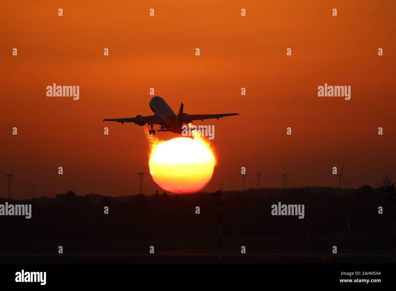Plane taking off into the sunset with a few windturbines in the ...