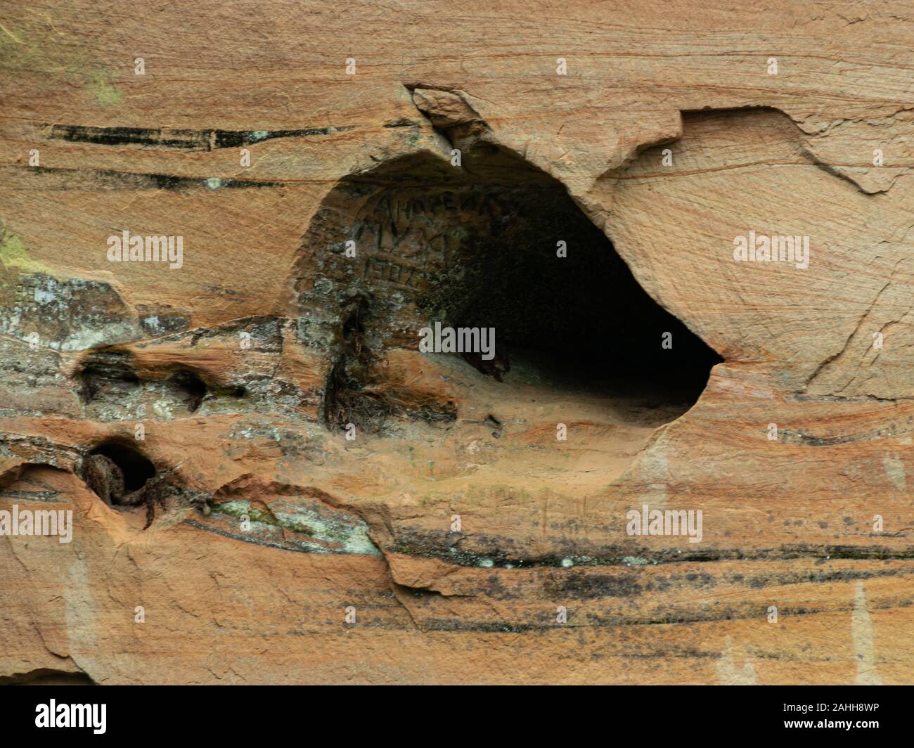 a landscape with a steep river and caves on a sandstone cliff, a cloudy ...