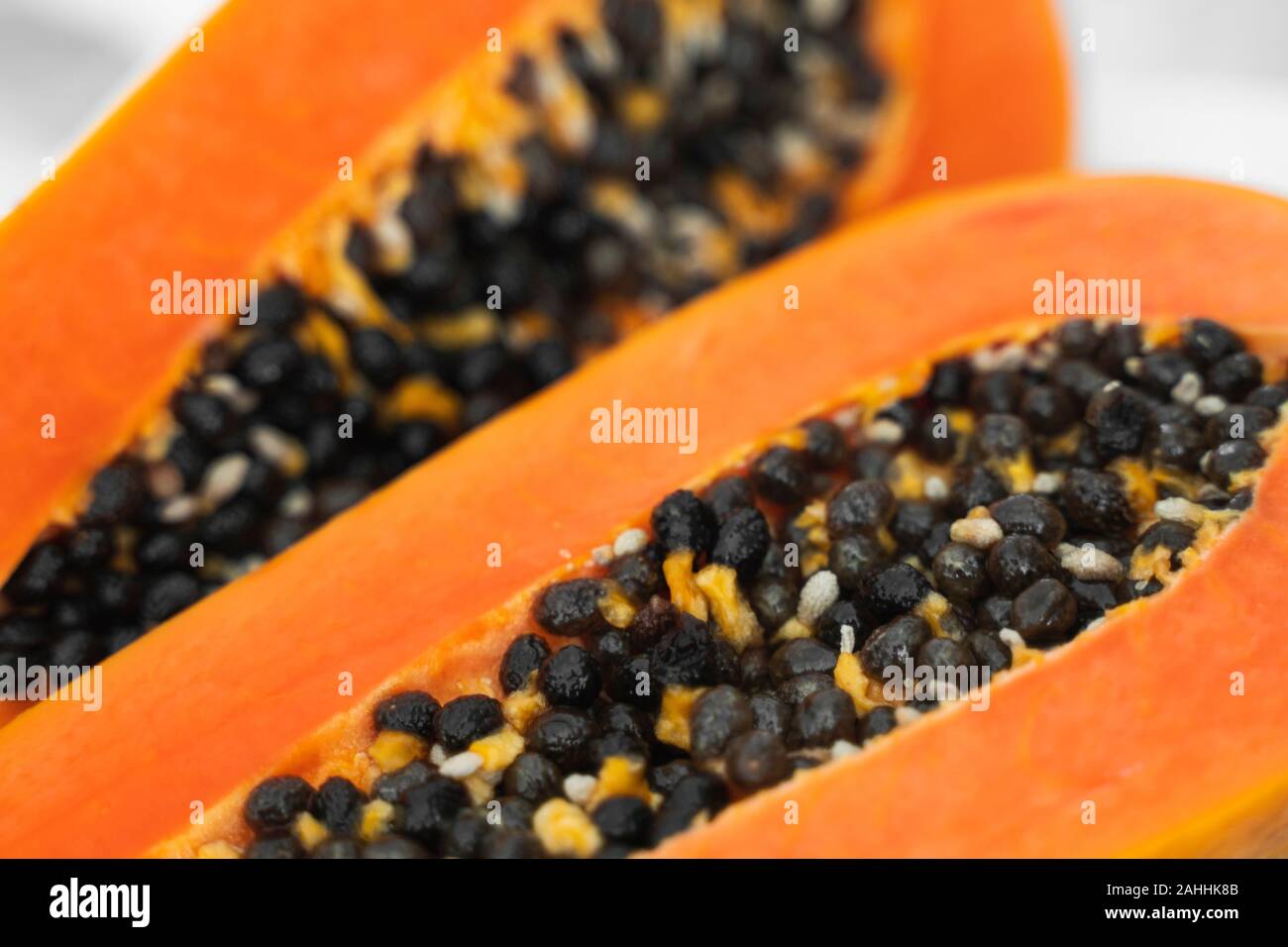 Half cut ripe papaya with seed on a white plate. Slices of sweet papaya ...