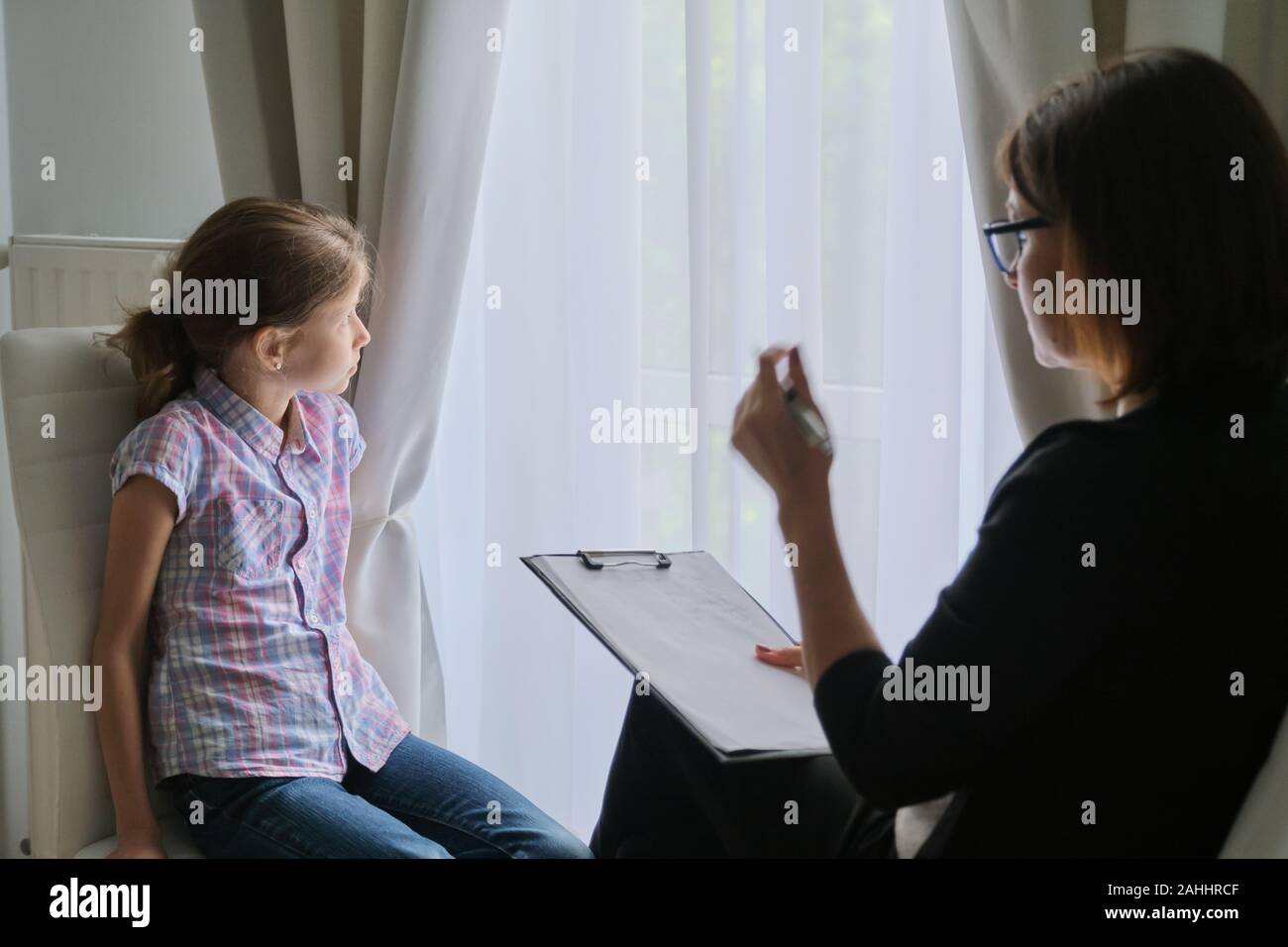 Woman social worker psychologist talking to girl child in office ...