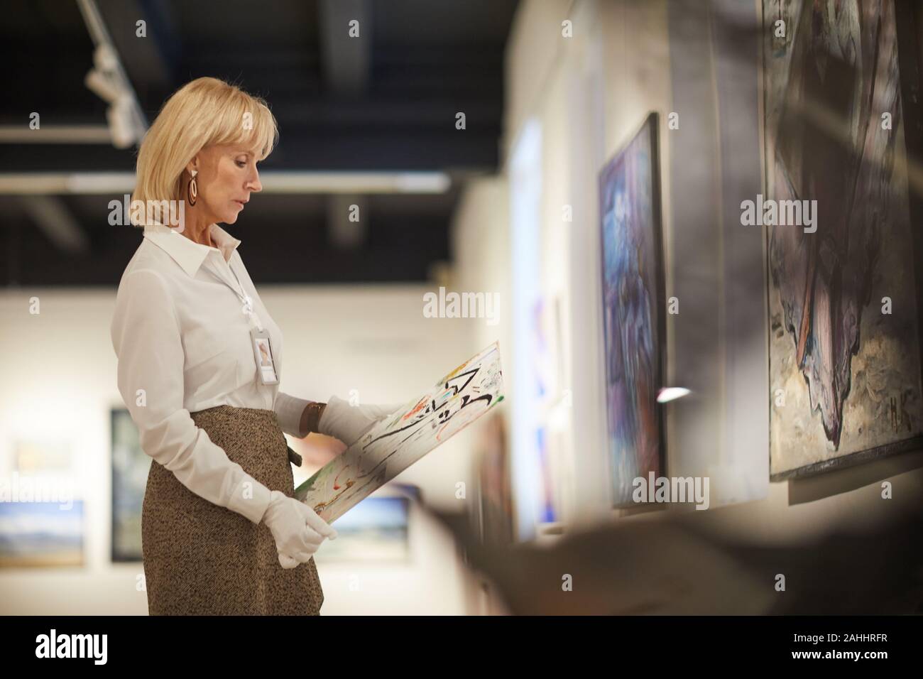 Side view portrait of female art expert appraising paintings in modern ...