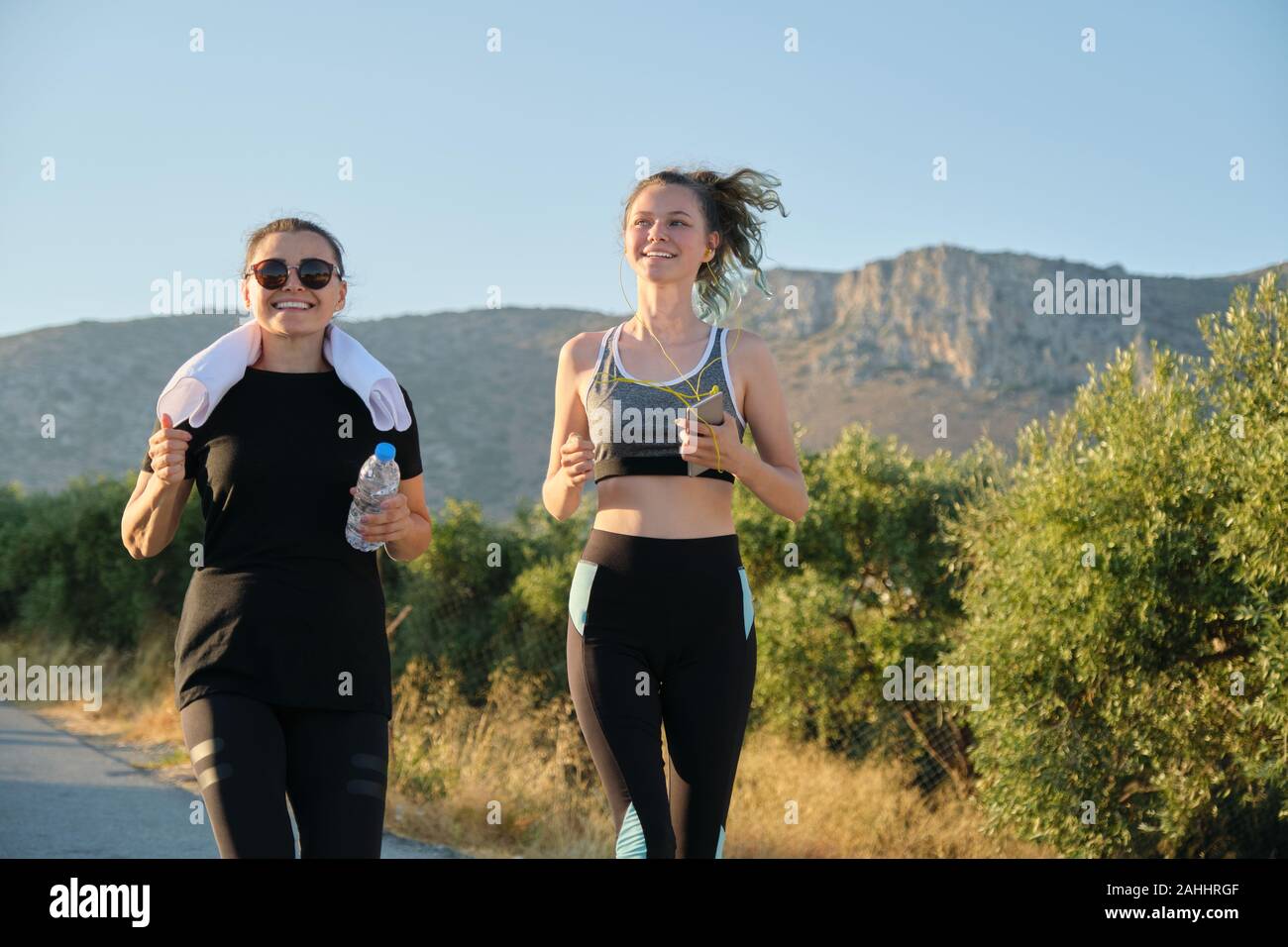 Two running women. Mother and daughter teenager running outdoor on road ...