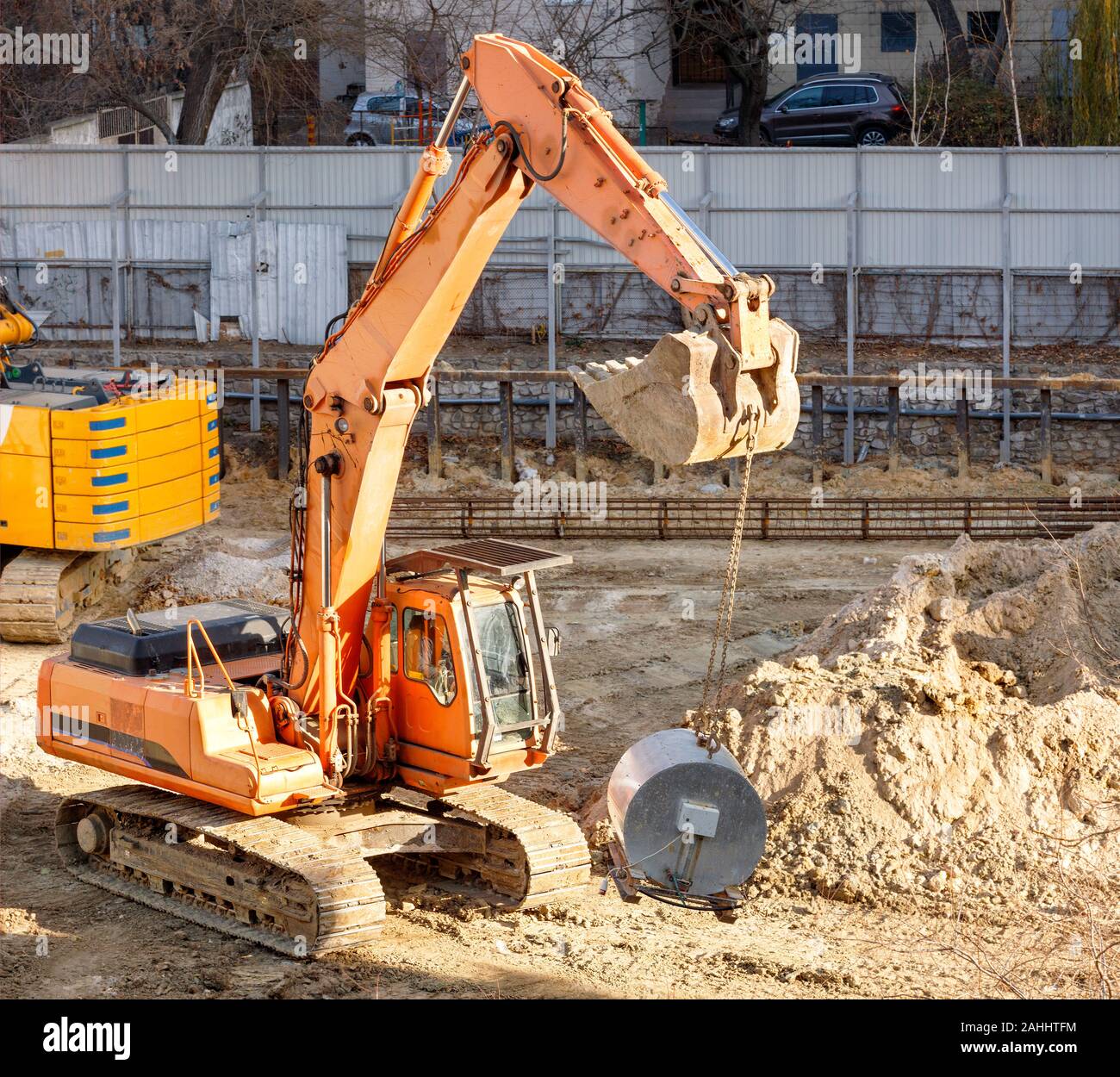 A heavy crawler construction excavator works on a fenced construction ...