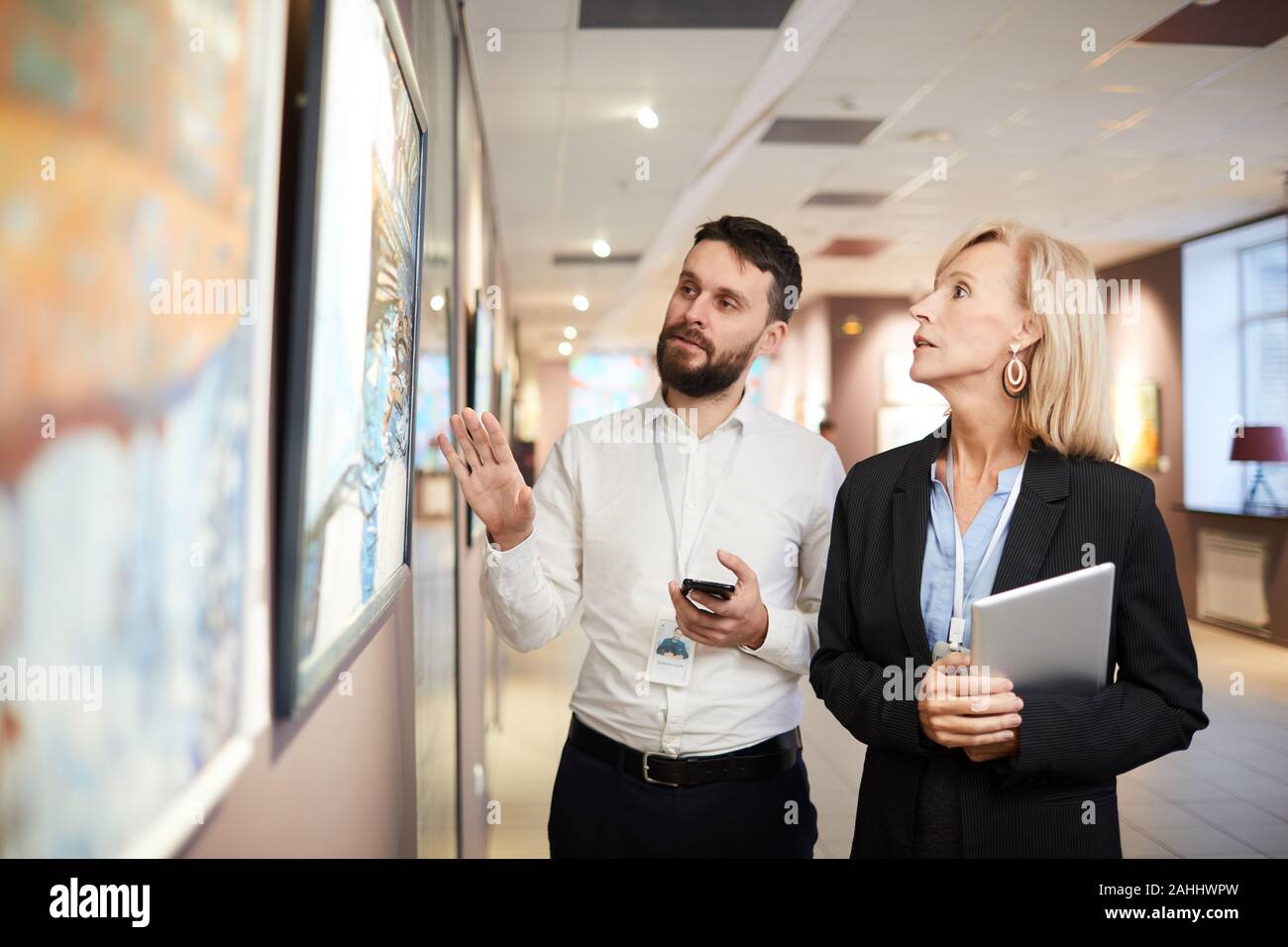Waist up portrait of art gallery manager consulting female expert or ...