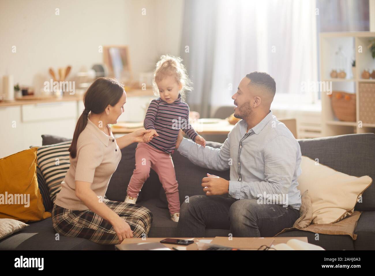 Warm toned portrait of happy modern family playing with cute little ...
