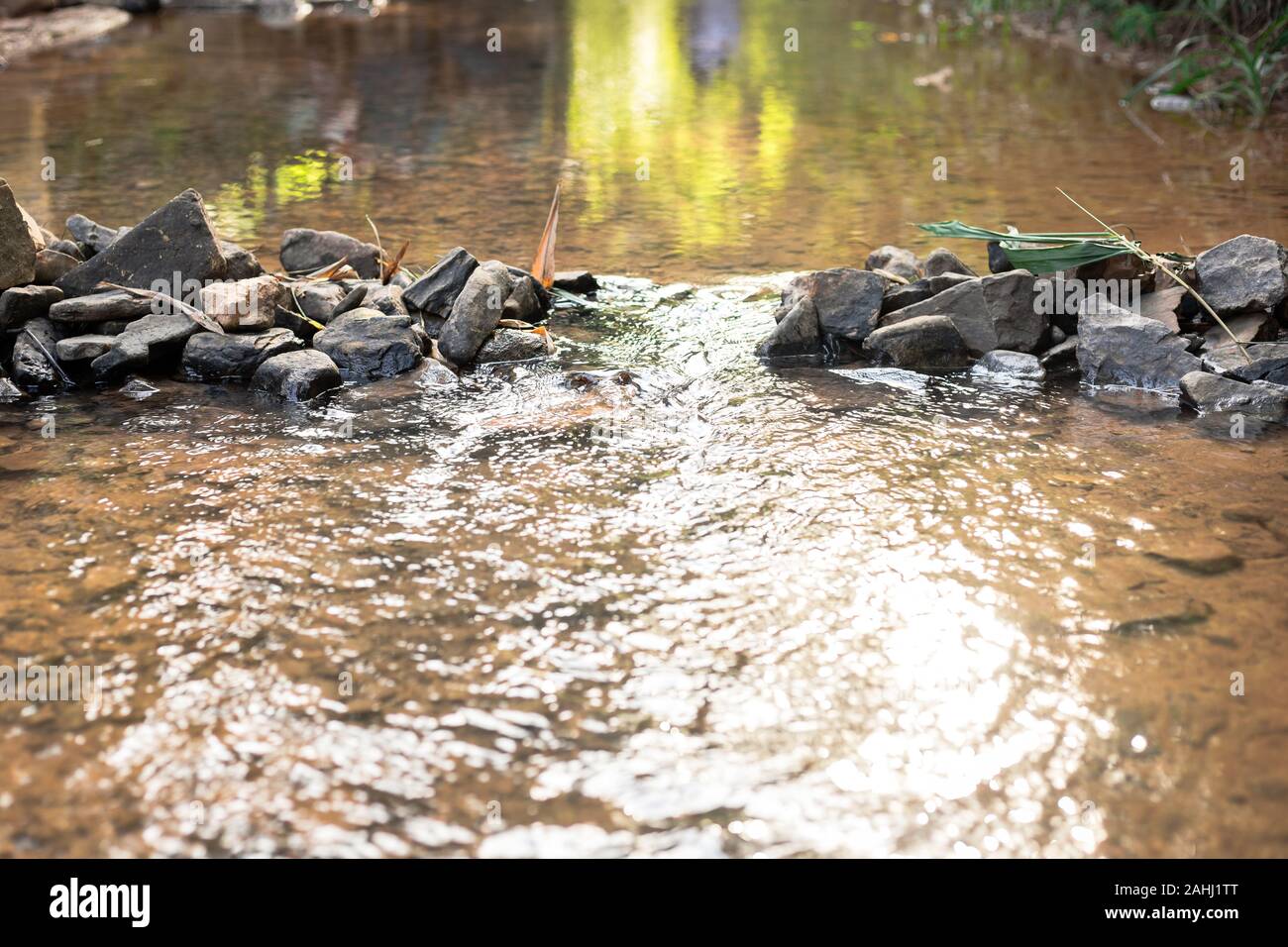 weir in river made from natural stone with people reflection on top ...