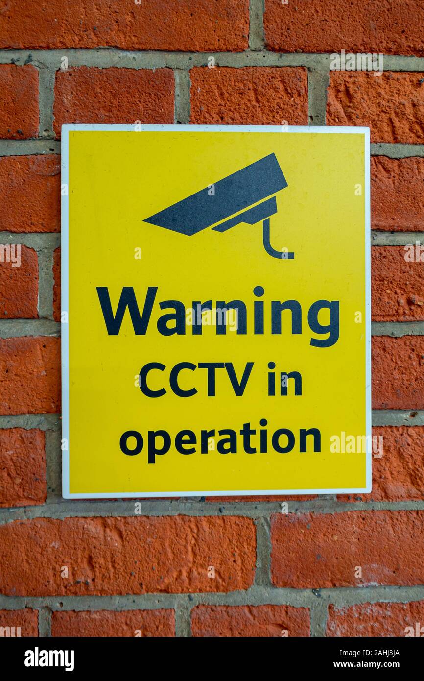 Yellow and black Warning CCTV in operation sign on a red brick wall ...