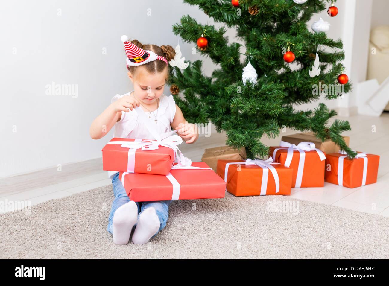Kid opening Xmas presents. Child under Christmas tree with gift boxes ...