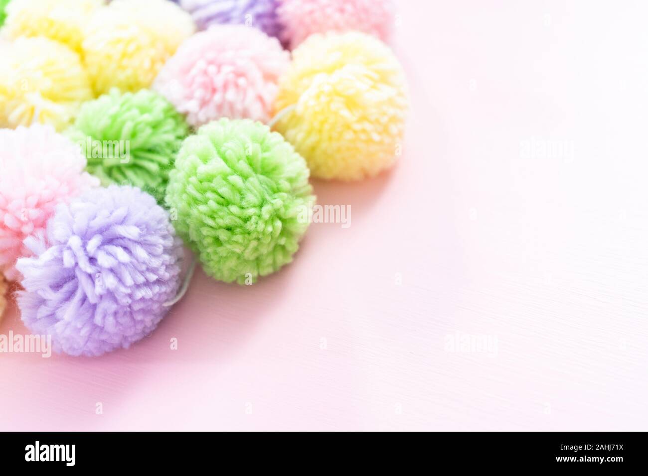 Pastel color pom poms on a pink background Stock Photo - Alamy