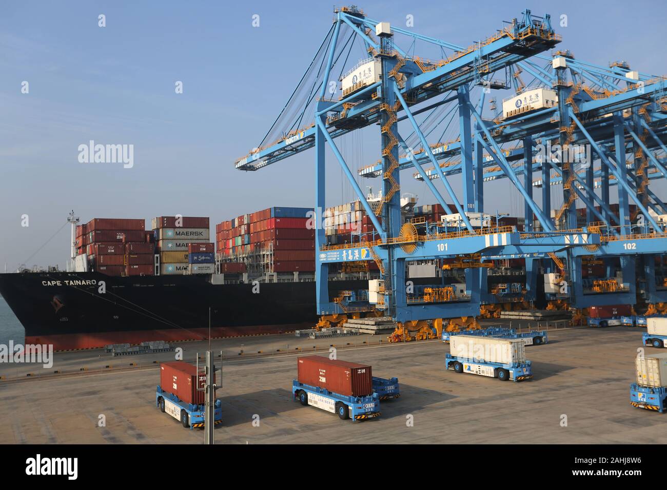 Unmanned container trucks transport containers unloaded from a ship on ...