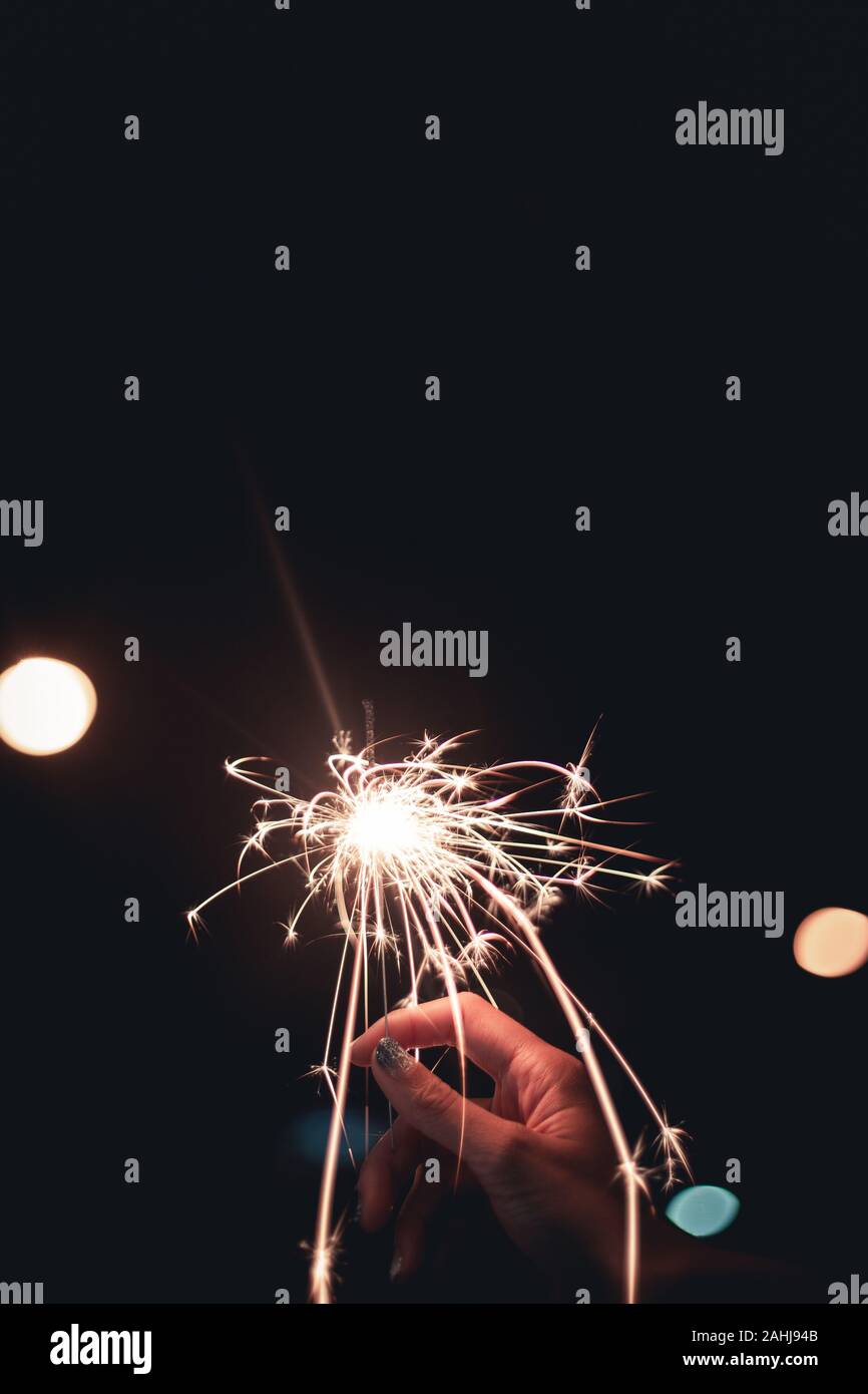 Woman's hand holding sparklers stick on fire, flame spread long light ...