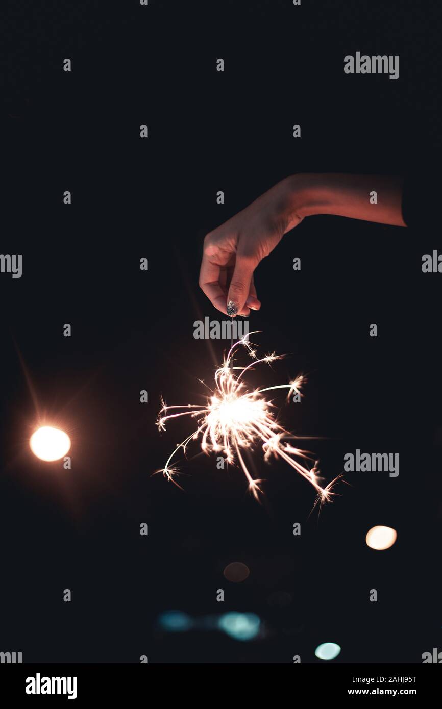 Woman's hand holding sparklers stick on fire from top drop down, flame ...