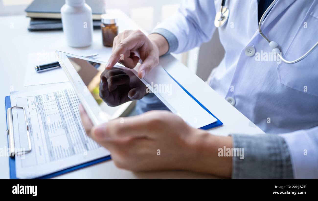 Doctor reading on a document report and writing on paperwork and ...