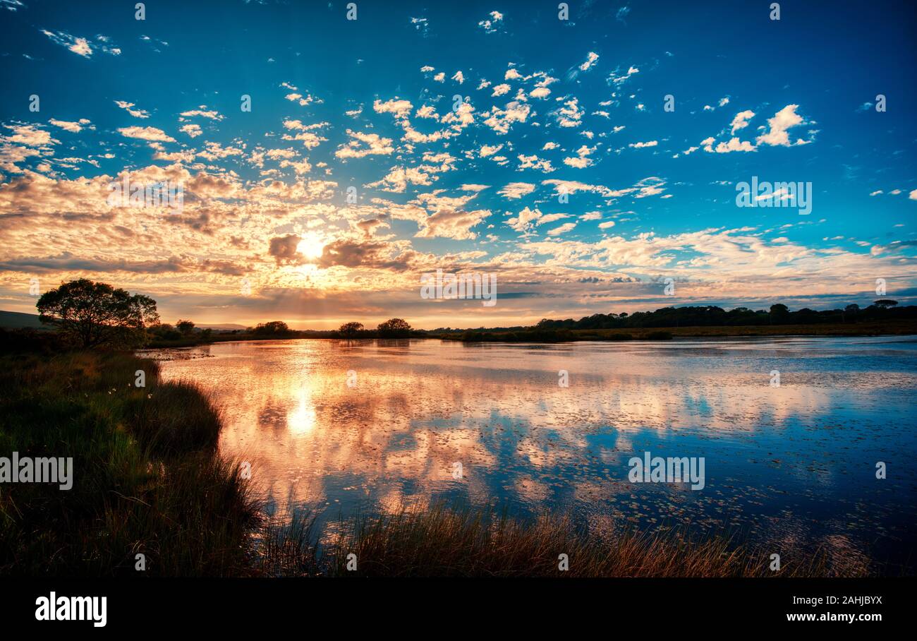 Sunset clouds and reflections off the surface of broad pool on the ...