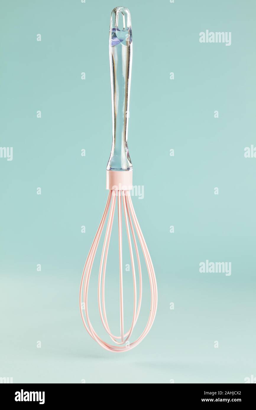 Single Pink silicone whisk on light blue background, vertical ...