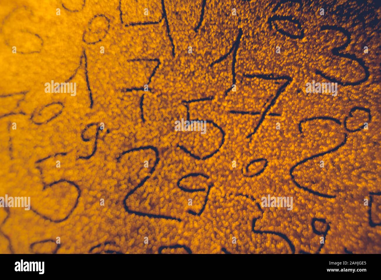 Hand drawn different numbers on shiny sand, a numerical background on ...