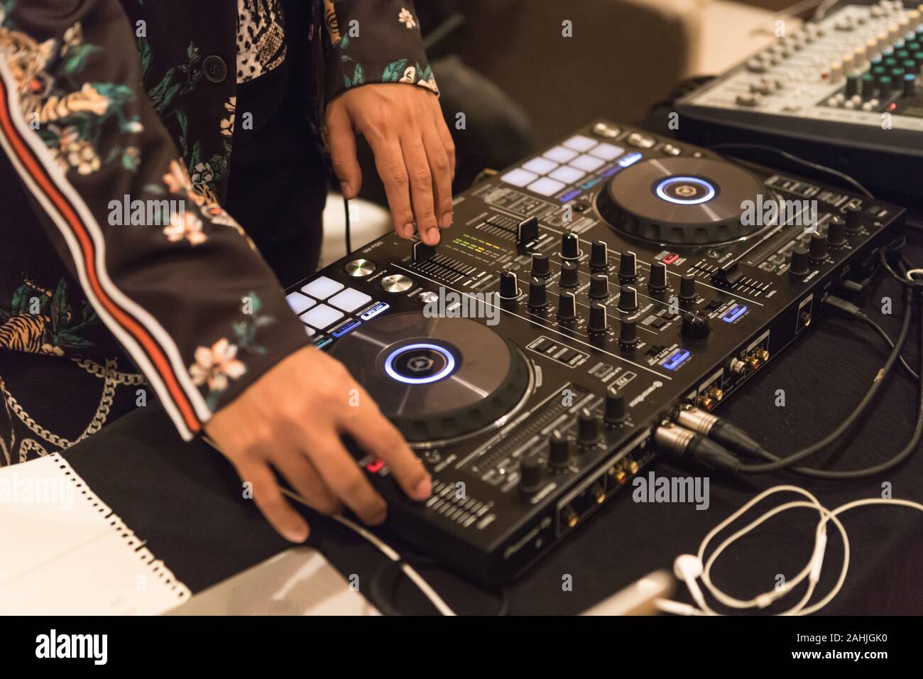 DJ in tiger pattern shirt is mixing some music with controller in the ...