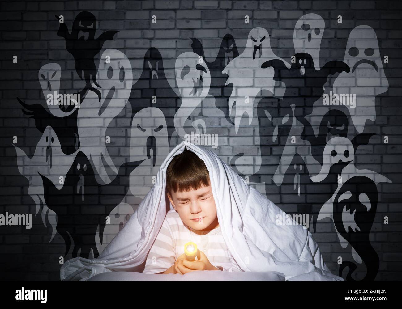 Frightened child with flashlight hiding under blanket. Scared kid with ...