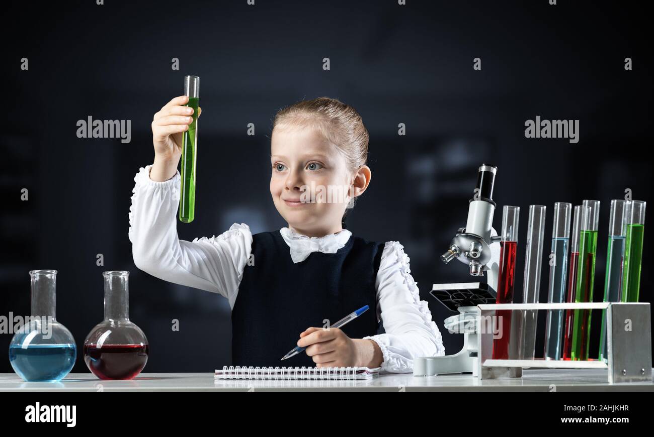 Little girl scientist examining test tube with chemical reagent ...