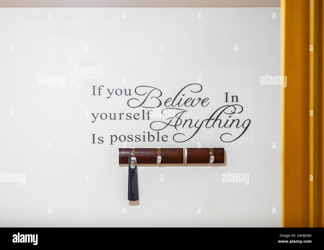 Motivating sign writing on a white wall. Wooden hanger on the wall for ...