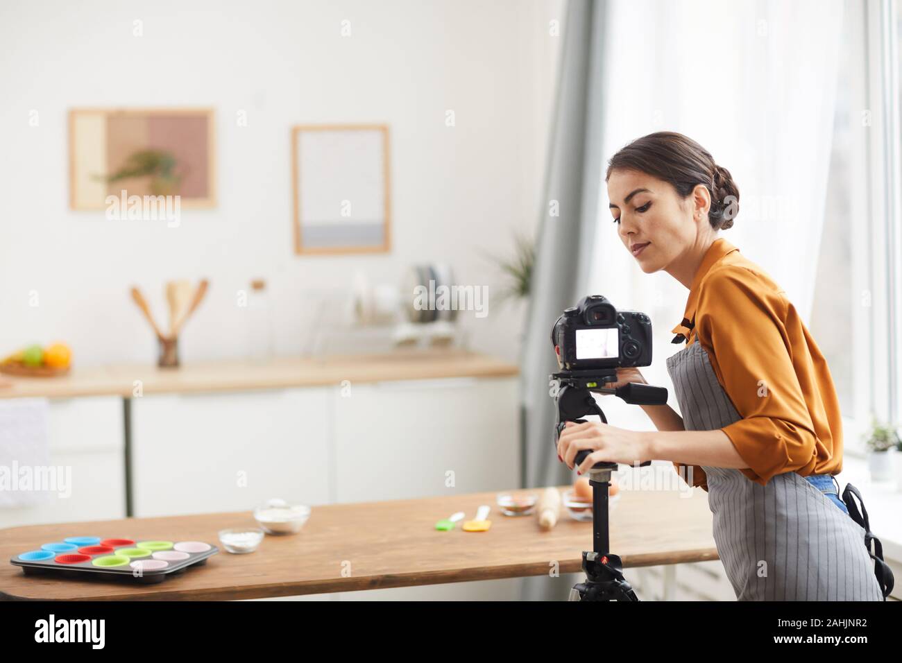 Waist up portrait of beautiful young woman setting up camera while ...