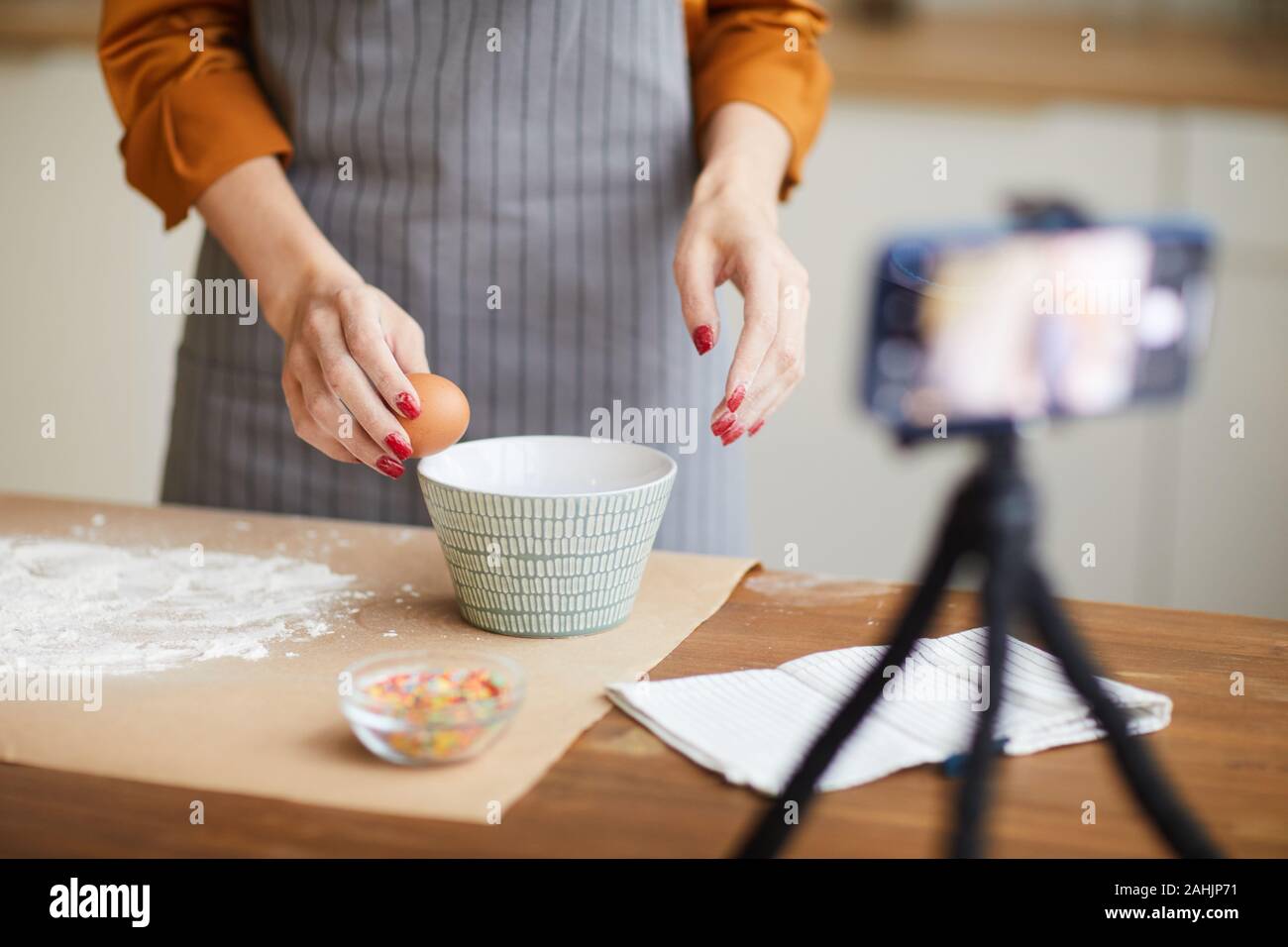 Cropped portrait of unrecognizable young woman breaking eggs while ...